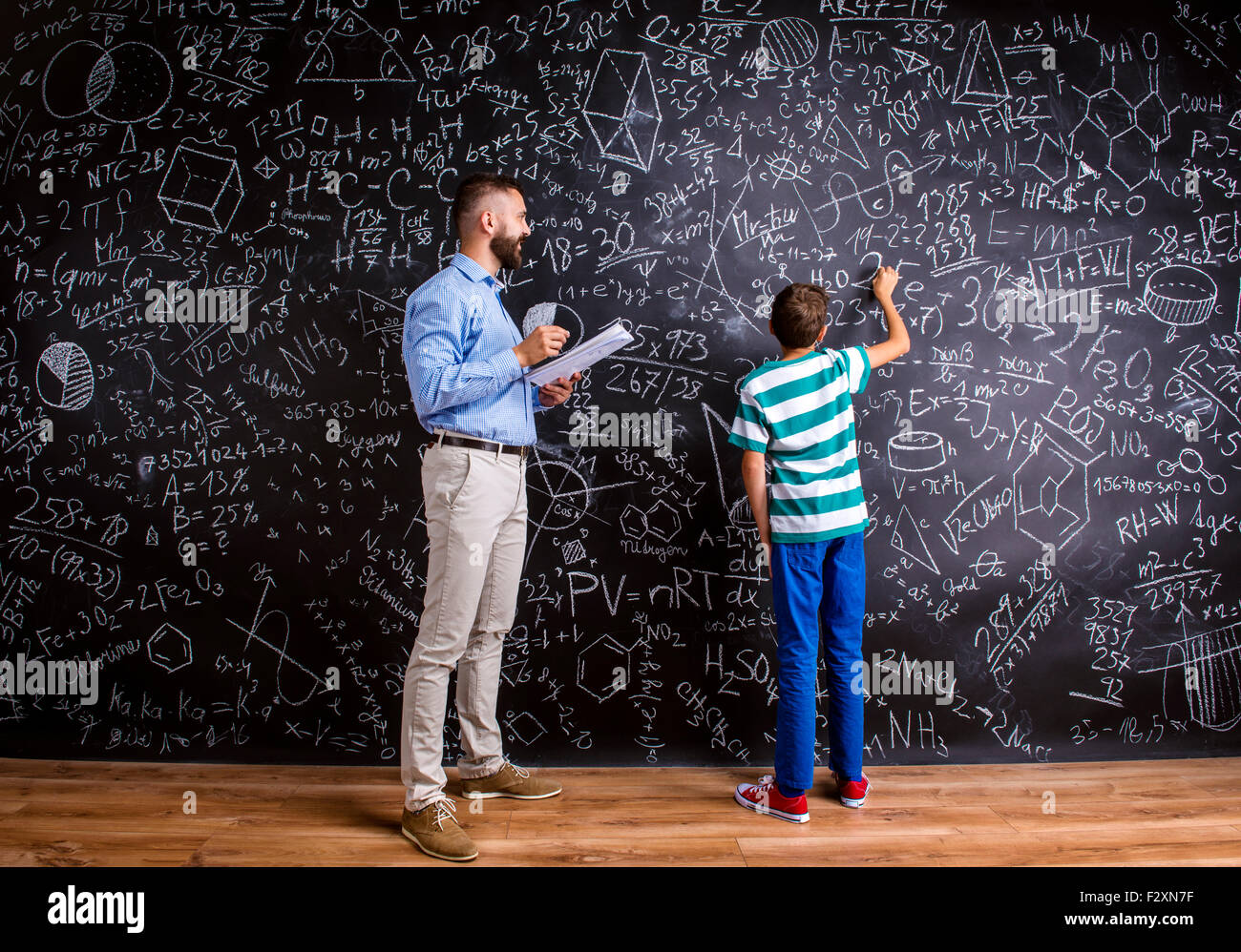 Young hipster school teacher with his pupil in front of big blackboard ...