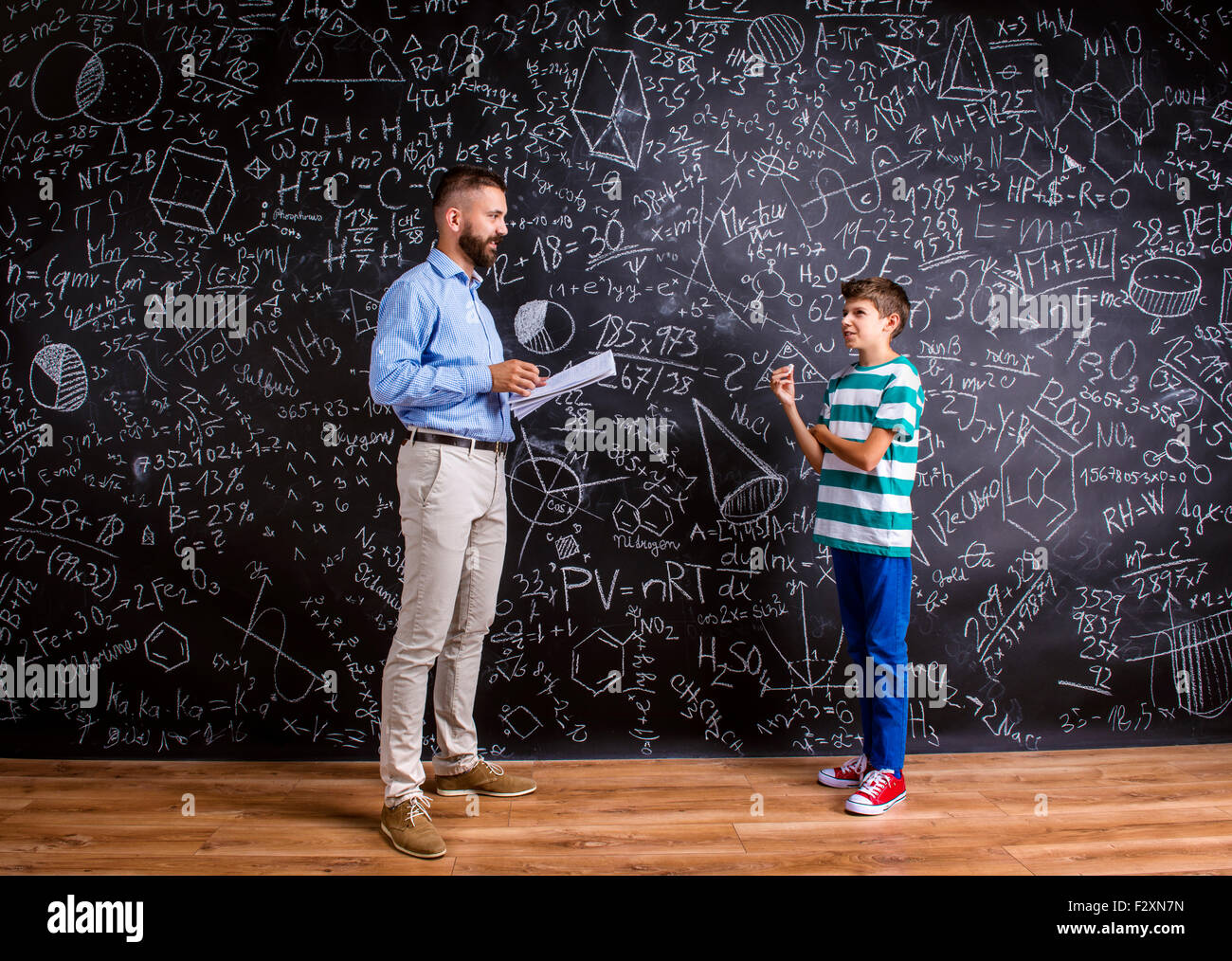 Young hipster school teacher with his pupil in front of big blackboard ...