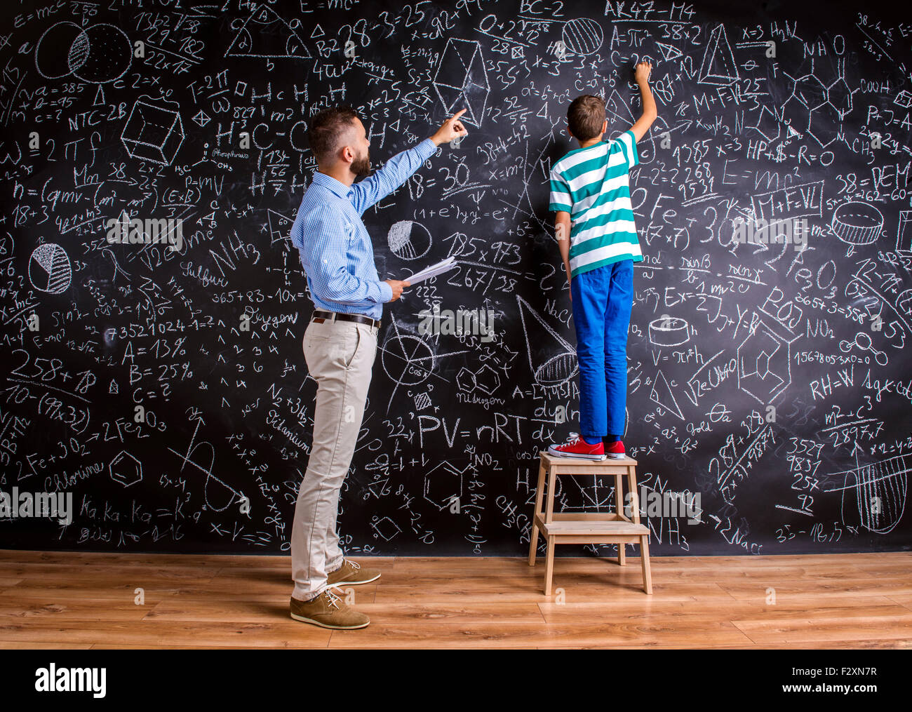 Young hipster school teacher with his pupil in front of big blackboard ...