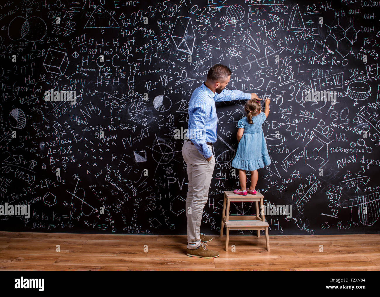 Young hipster school teacher with his pupil in front of big blackboard ...