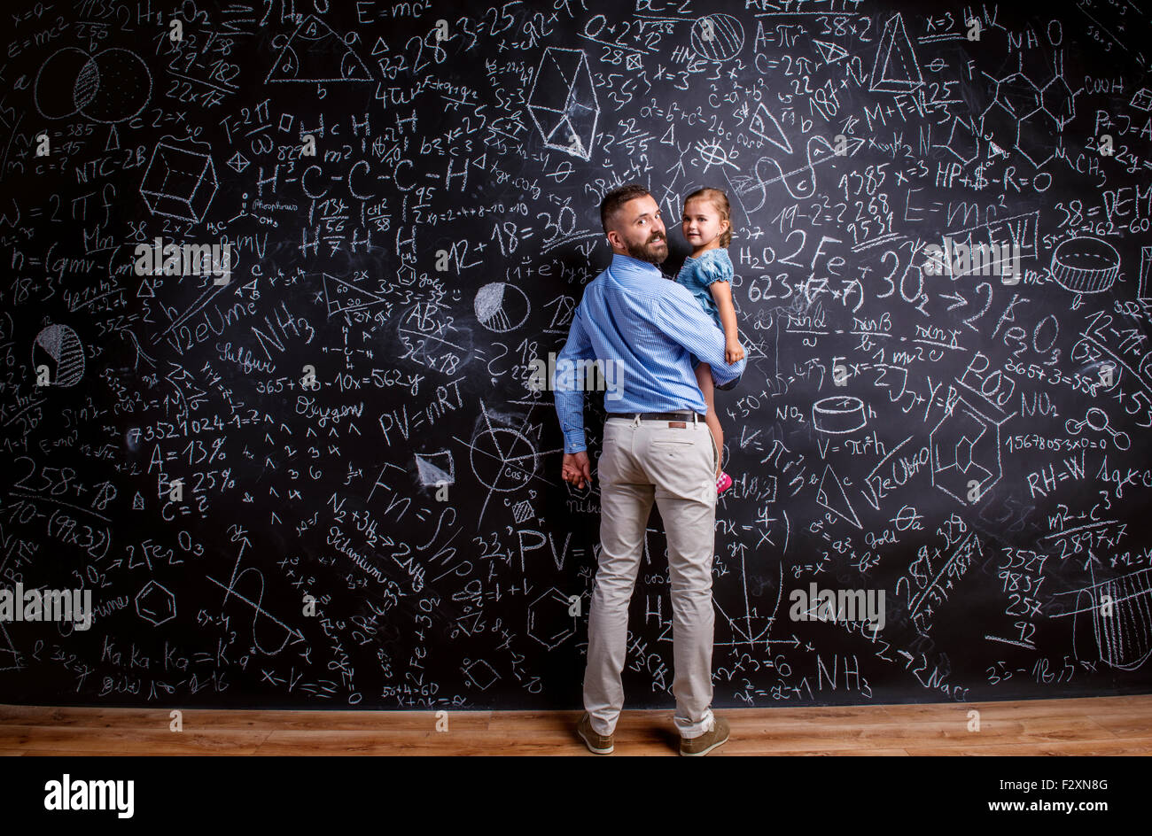 Young hipster school teacher with his pupil in front of big blackboard ...