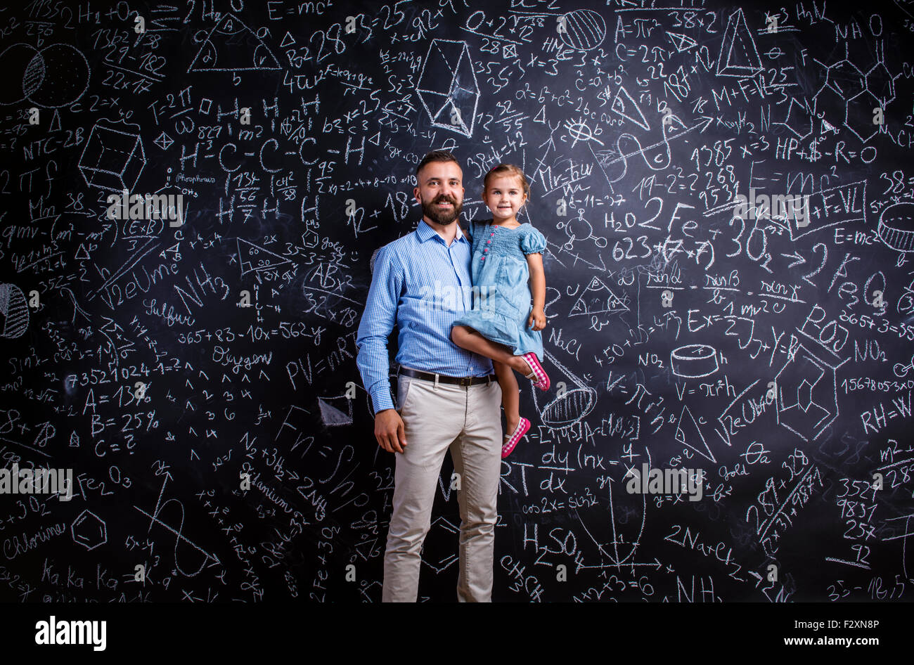 Young hipster school teacher with his pupil in front of big blackboard ...
