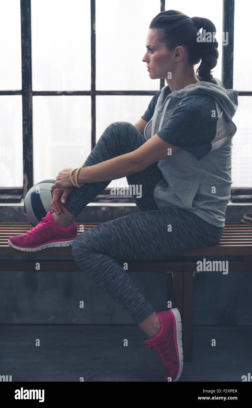 A woman is sitting relaxing while sitting on a wooden bench in a loft ...
