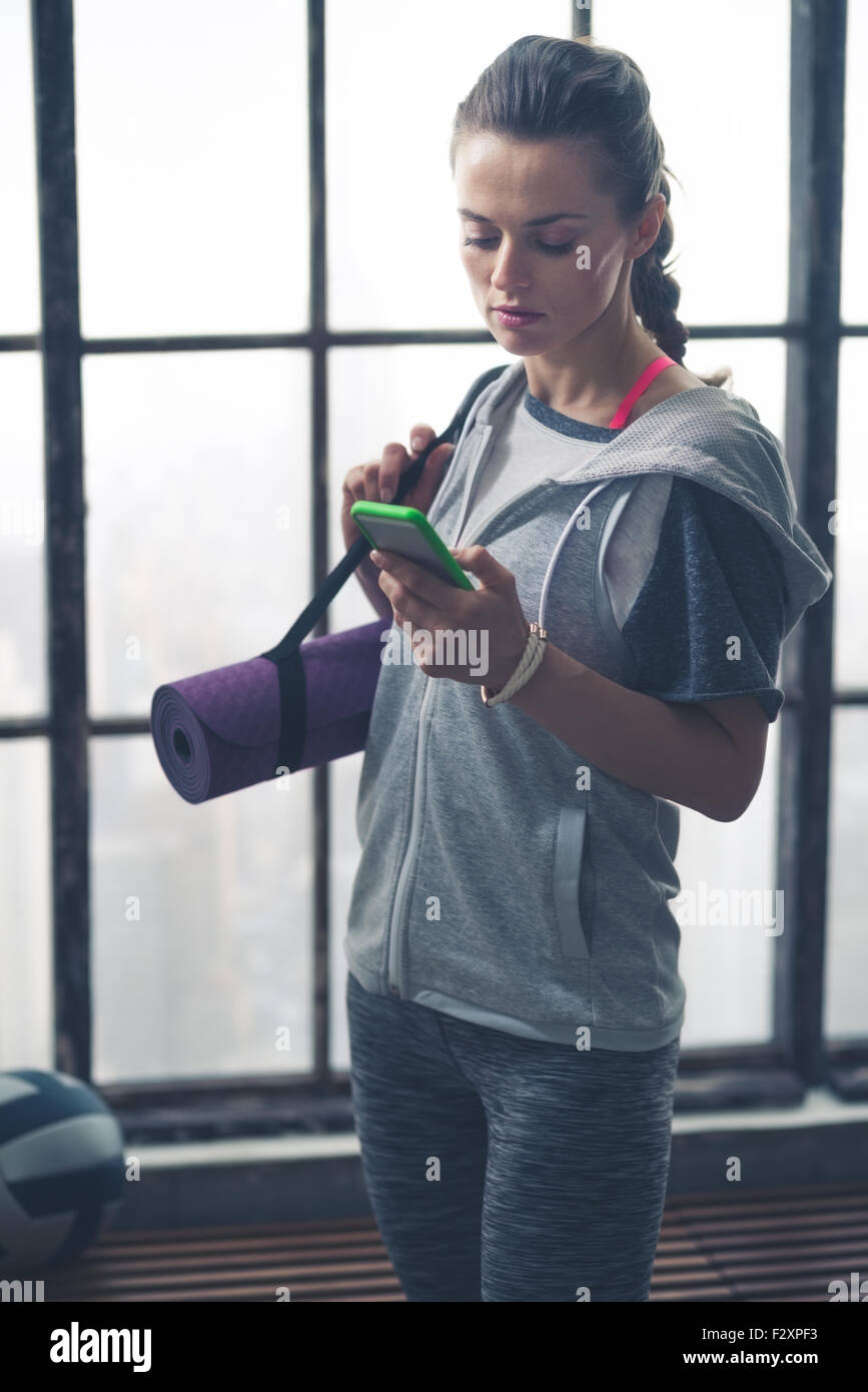 With her yoga mat slung over one shoulder, a fit, healthy woman is ...