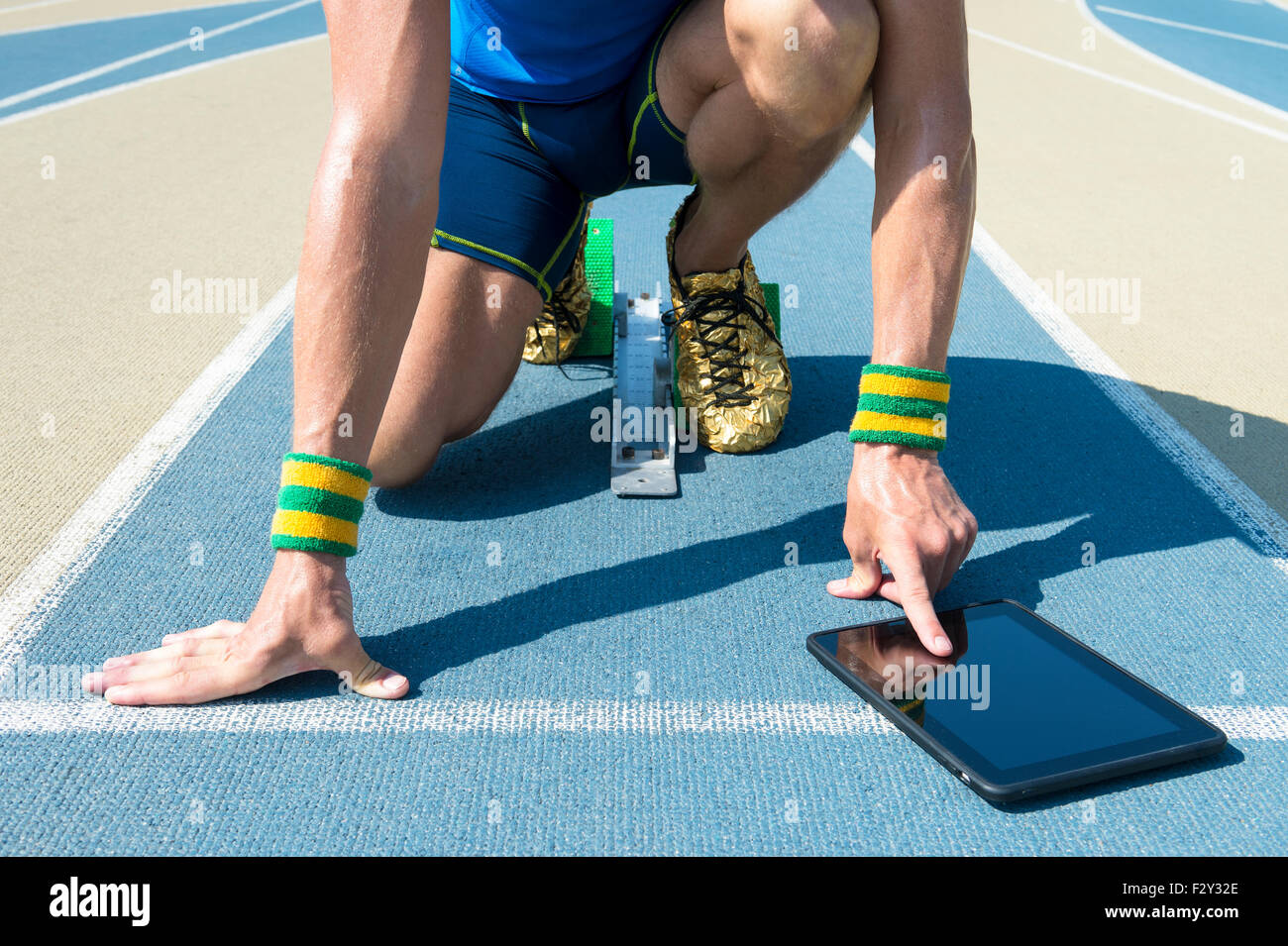 Athlete crouching at the starting line of a running track wearing ...