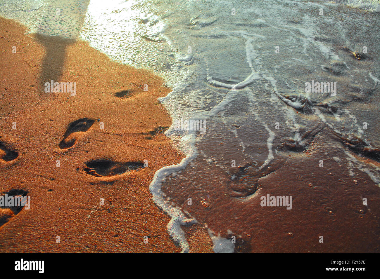 Calm sea surf and footsteps at sunset Stock Photo - Alamy