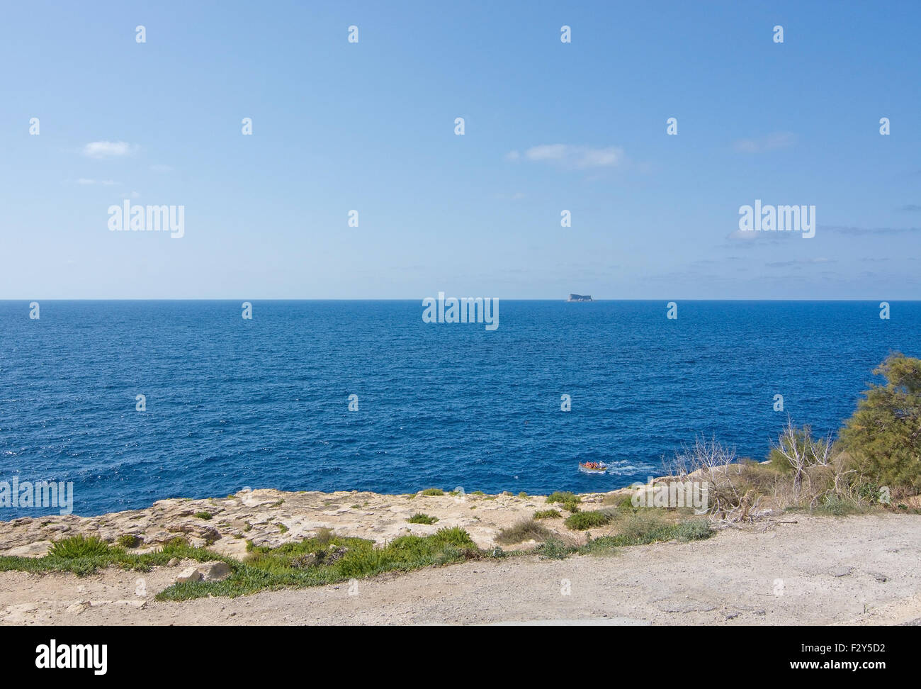 Bird island Filfla on the horizon and boat with people in the water of ...