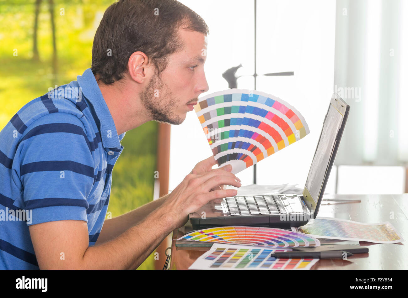 Man working on laptop while holding up palette, colormap from profile ...