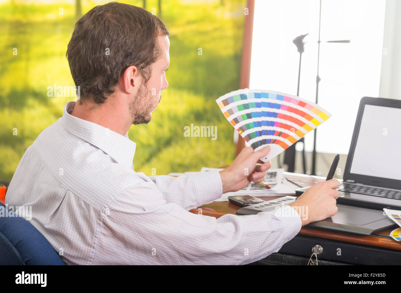 Man working on laptop while holding up palette, colormap from profile ...