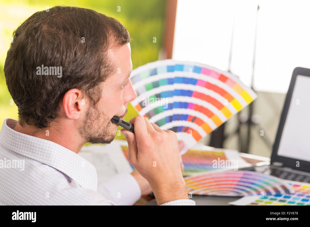 Man working on laptop while holding up palette, colormap from behind ...