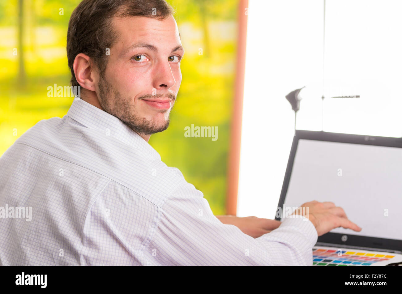 Man working on laptop turning around towards camera Stock Photo - Alamy