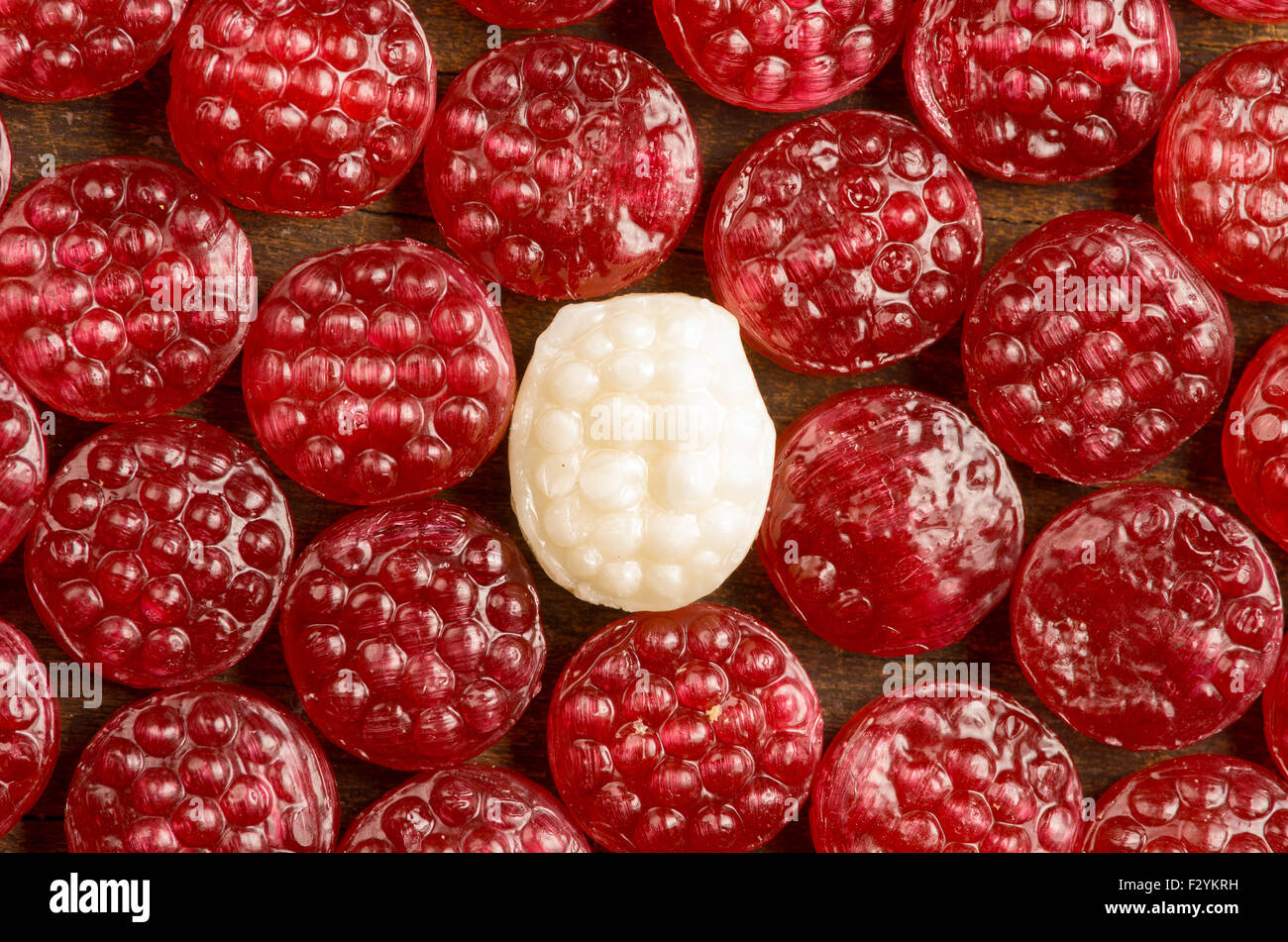 Pile of tasty delicious raspberry hard candy lying on wooden surface ...