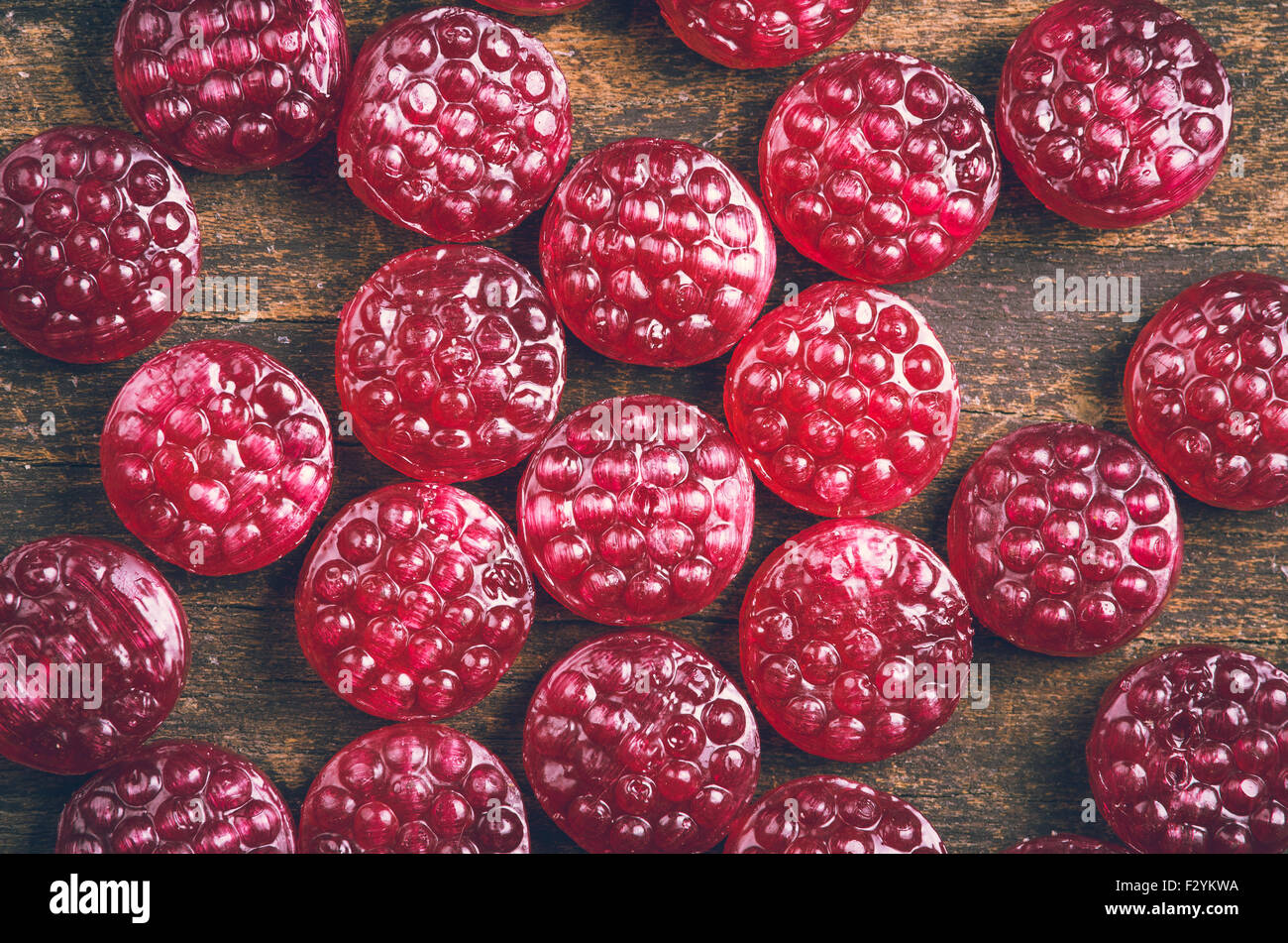 Pile of tasty delicious raspberry hard candy lying on wooden surface ...