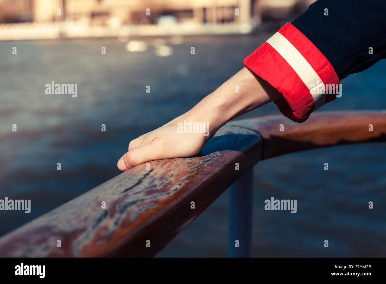 Closeup on a woman's hand holding the railing on the deck of a ship ...
