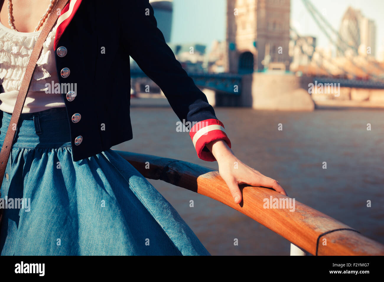 Young woman is holding and leaning against the rail on the deck of a ...