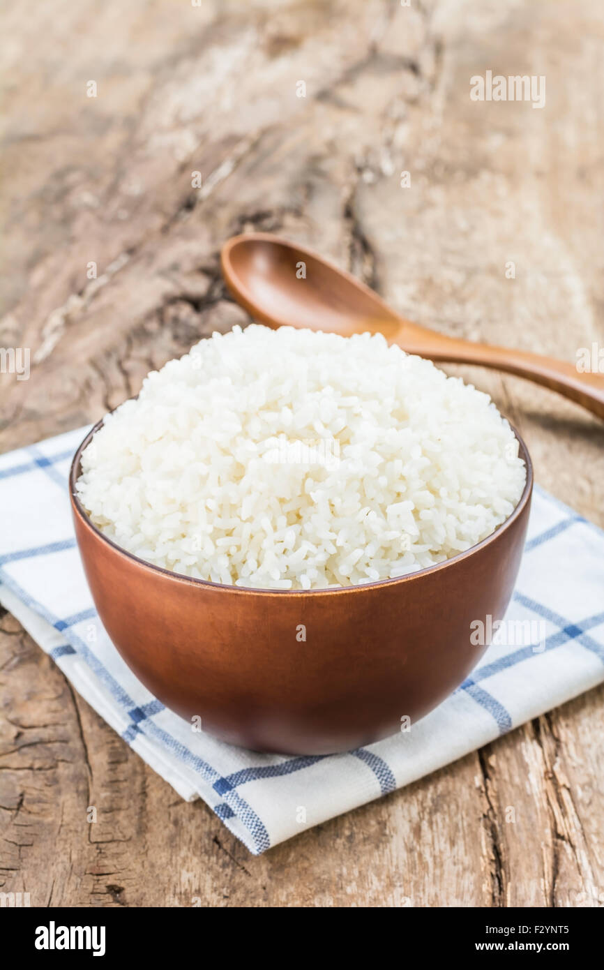 Cooked rice in bowl with dishcloth and spoon on old wooden table Stock ...