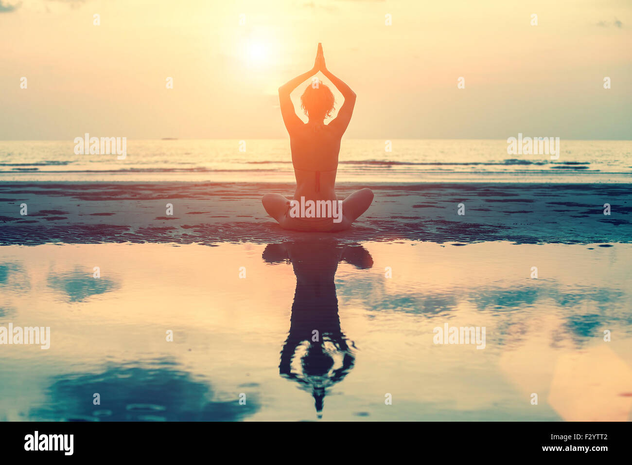 Female silhouette in yoga with reflection in water, meditation pose at ...