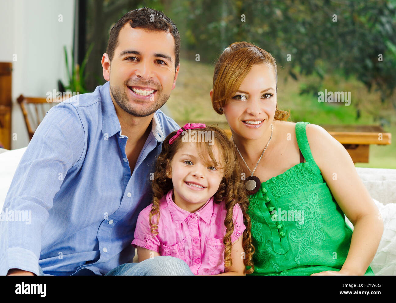 Proud happy hispanic parents posing with little cute girl wearing pink ...