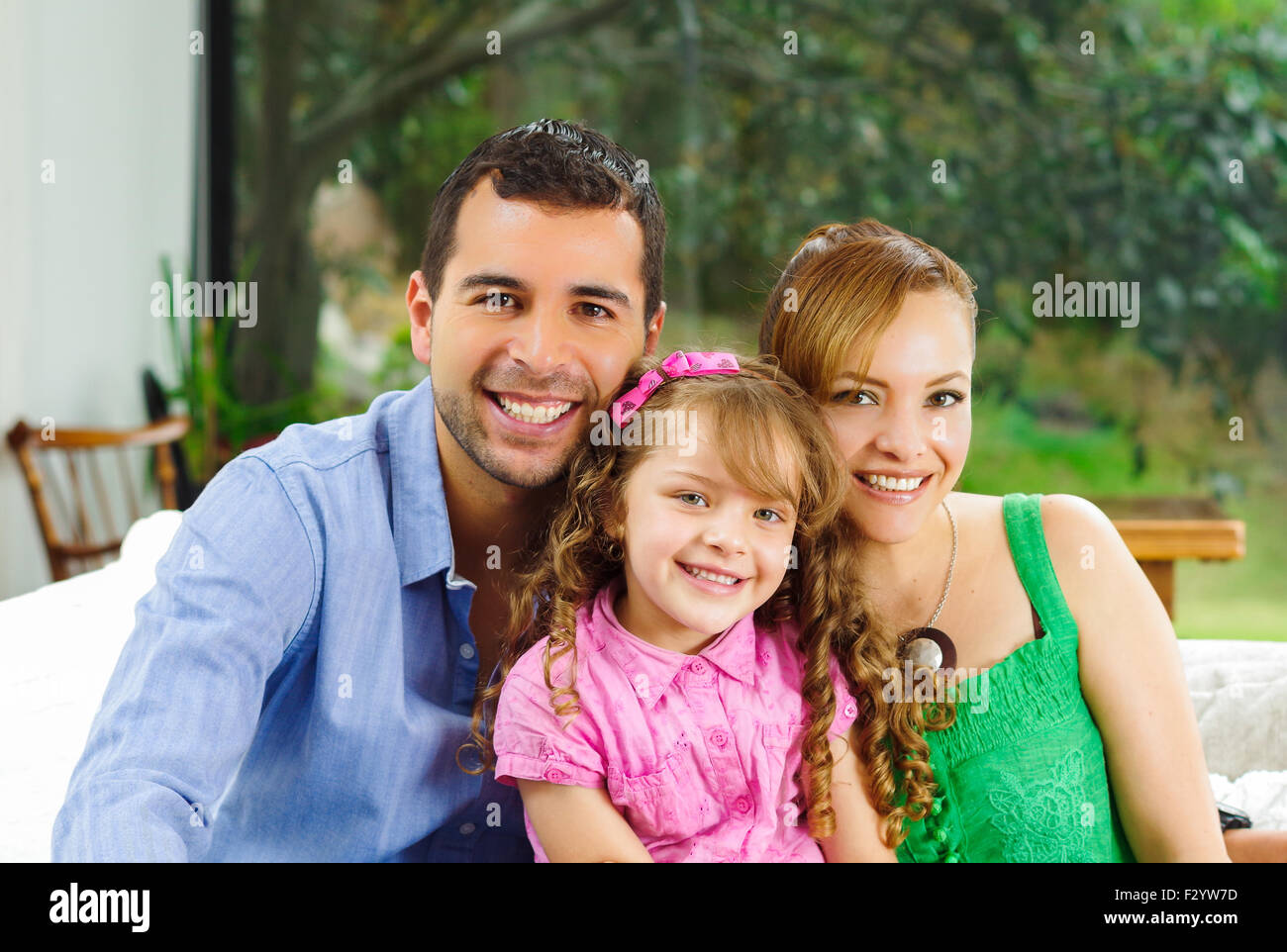 Proud happy hispanic parents posing with little cute girl wearing pink ...