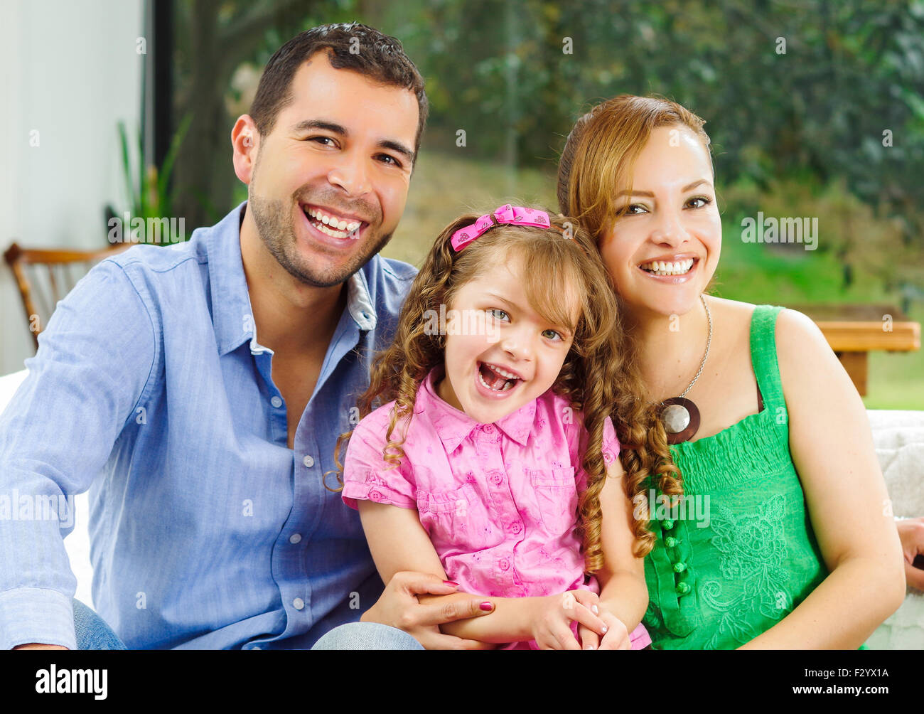 Proud happy hispanic parents posing with little cute girl wearing pink ...