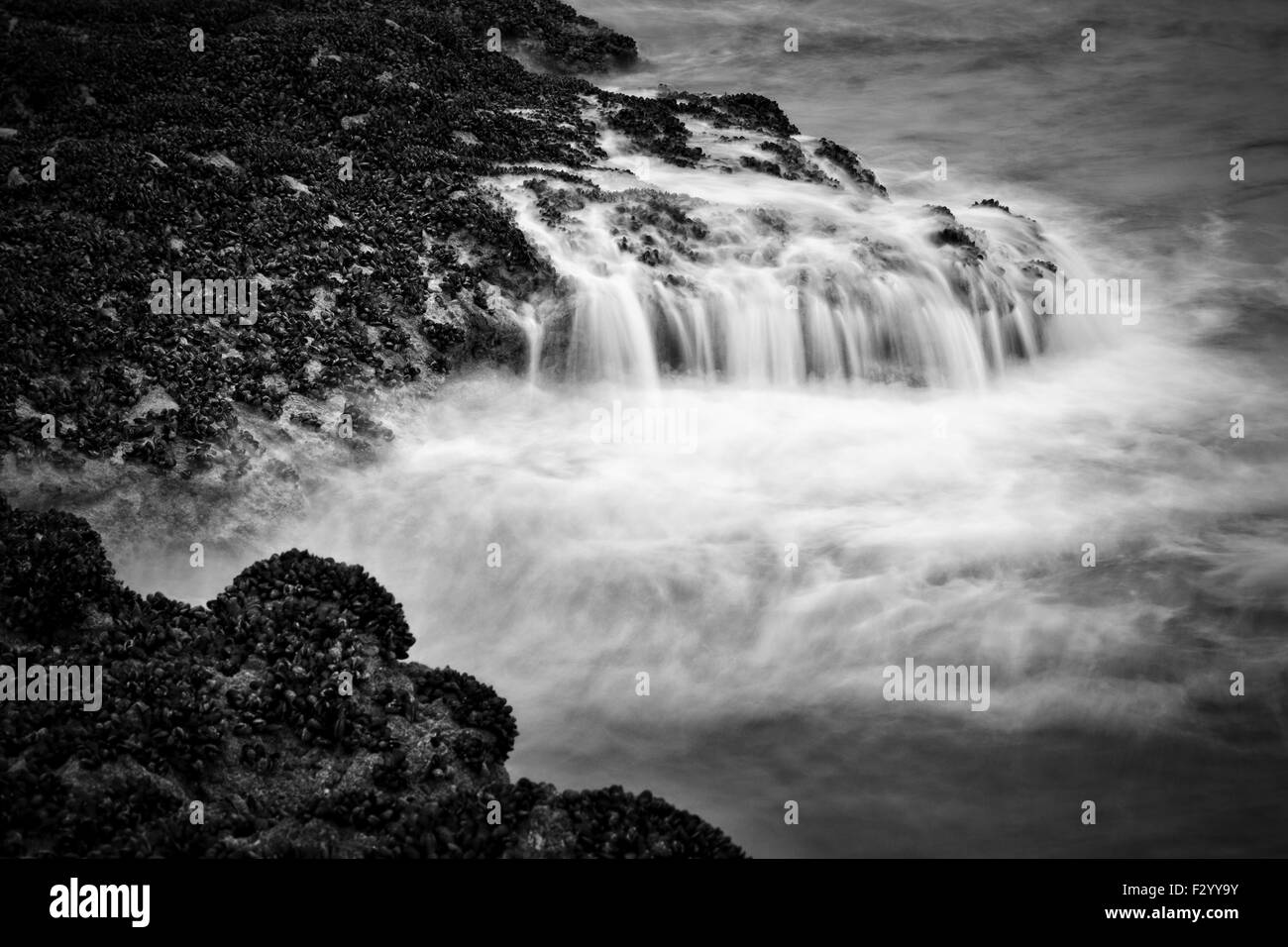 Wave cascading over rock Stock Photo - Alamy