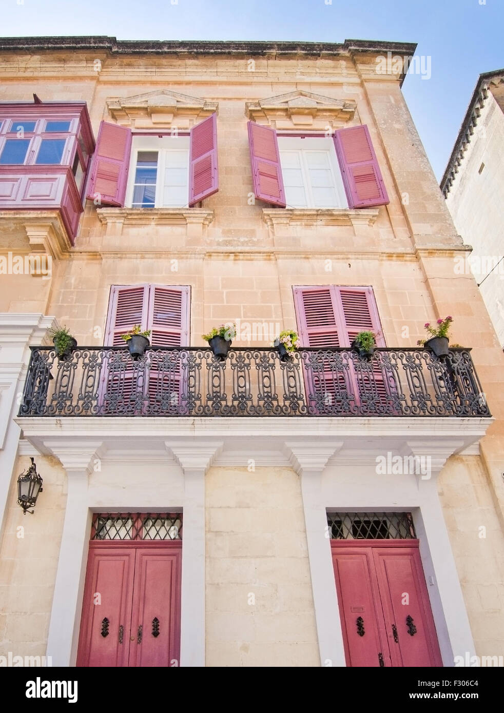 Building with red window shutters and black wrought iron balcony inside ...