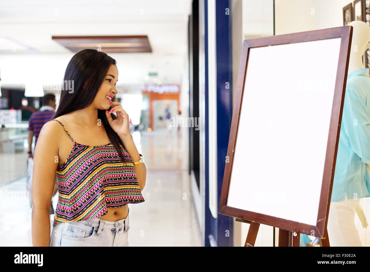 young woman in a shopping center looking at a blank sign Stock Photo ...