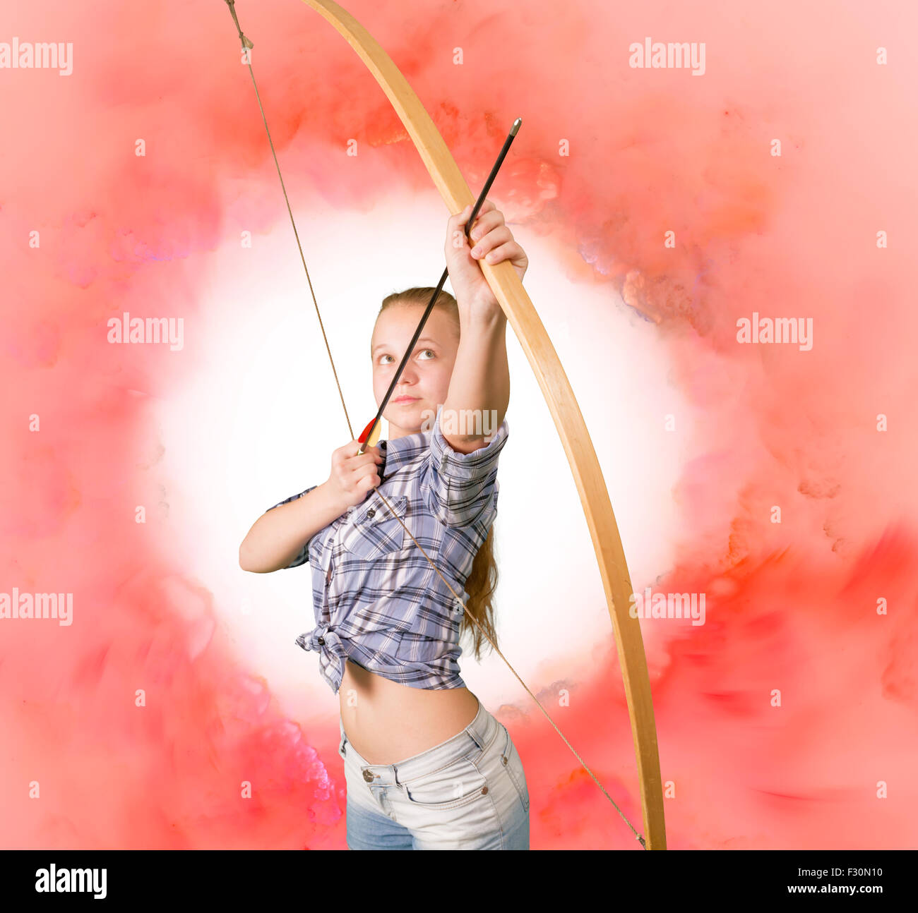 Teen girl practicing archery pink cloud background Stock Photo - Alamy