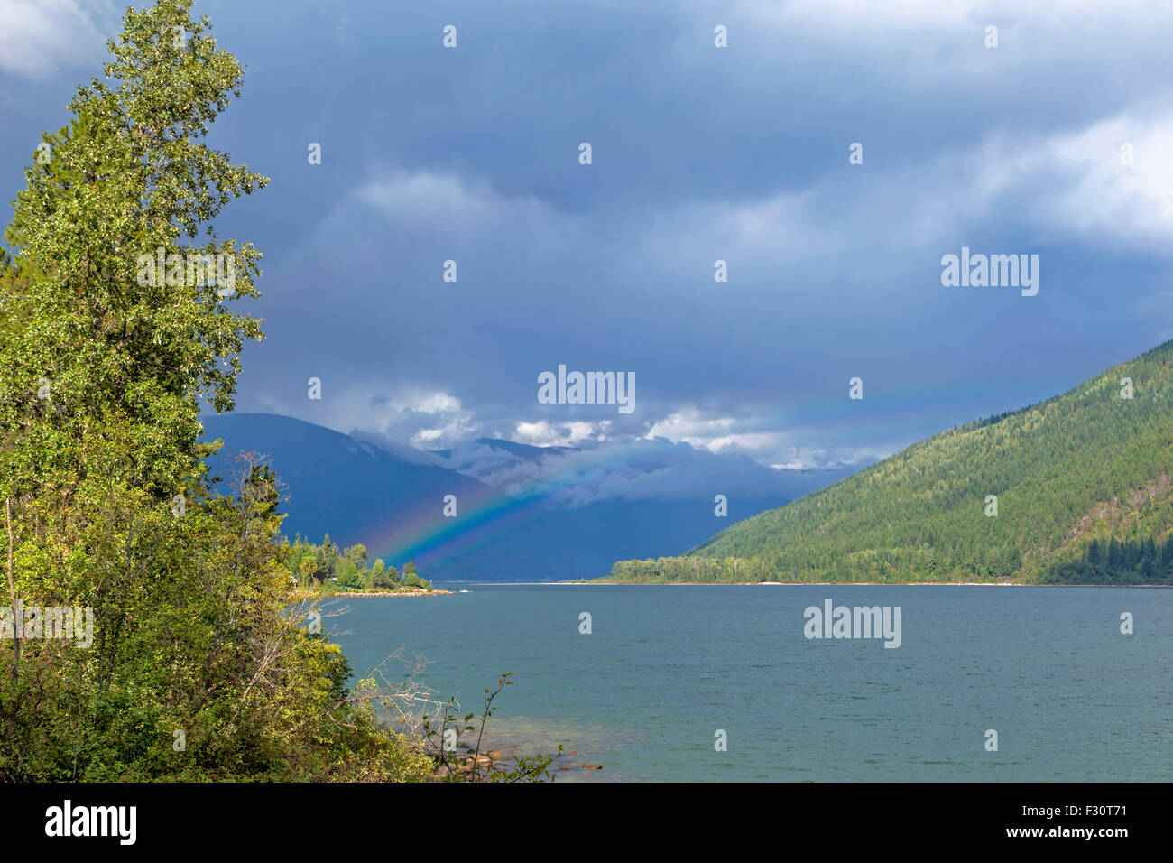 A colorful rainbow above Kootenay Lake and surrounding mountains ...