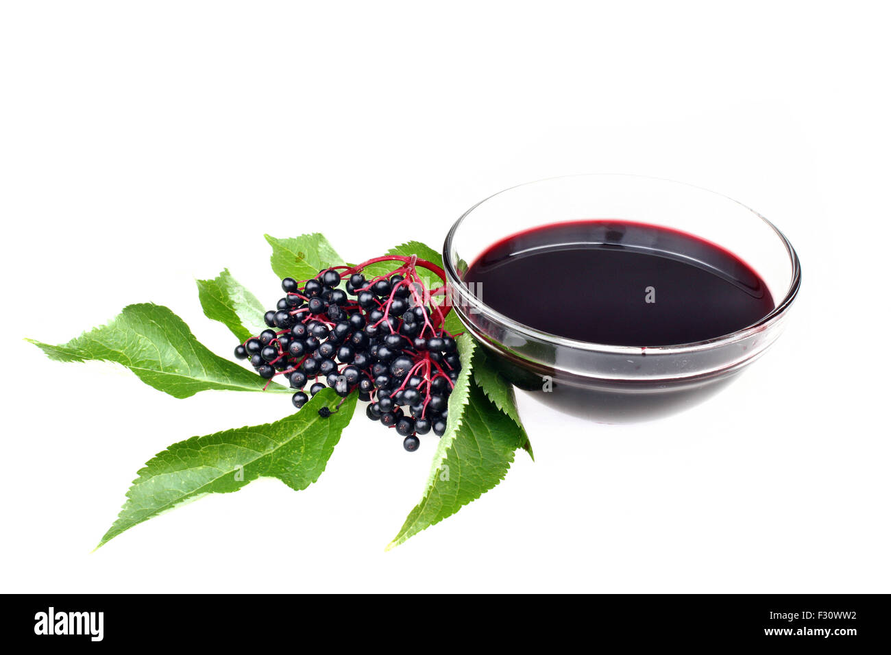 Bunch of fresh elderberry with green leaves and glass of elderberry ...