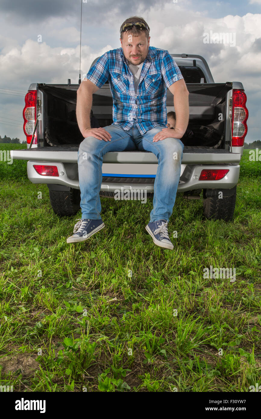 Solid man sitting on car trunk on natural background Stock Photo - Alamy