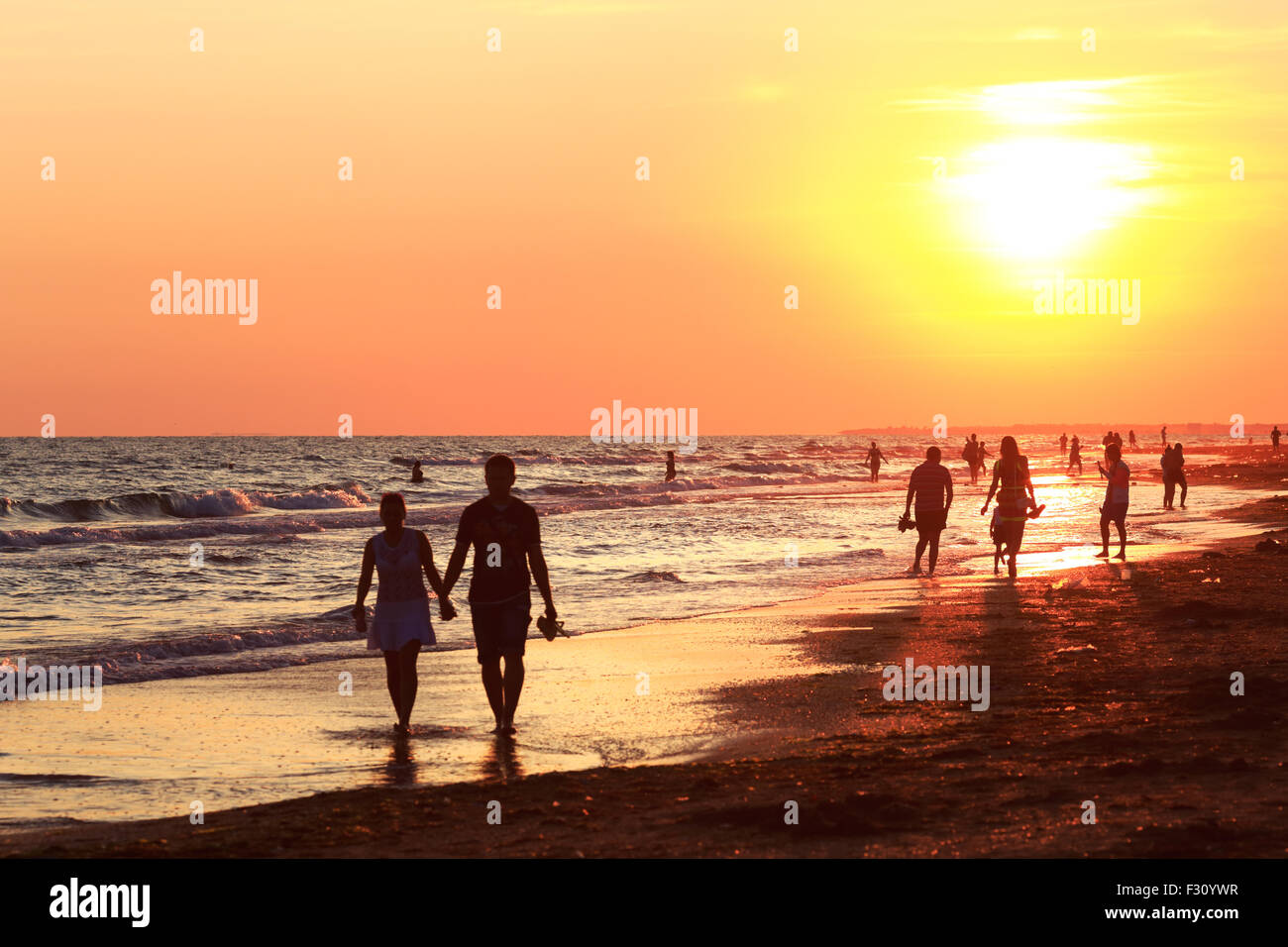 People walking on the beach at sunset Stock Photo - Alamy