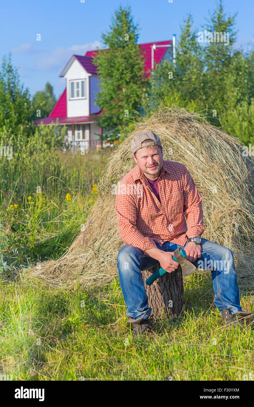 Farmer with an axe on haystack on background Stock Photo - Alamy