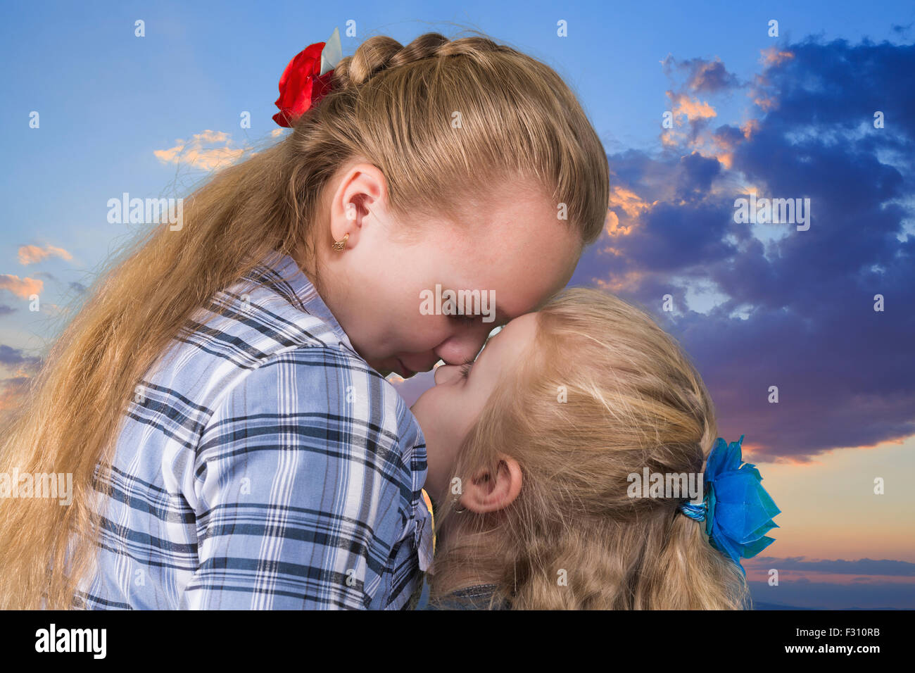 Senior and junior sisters embracing and kissing on abstract background ...
