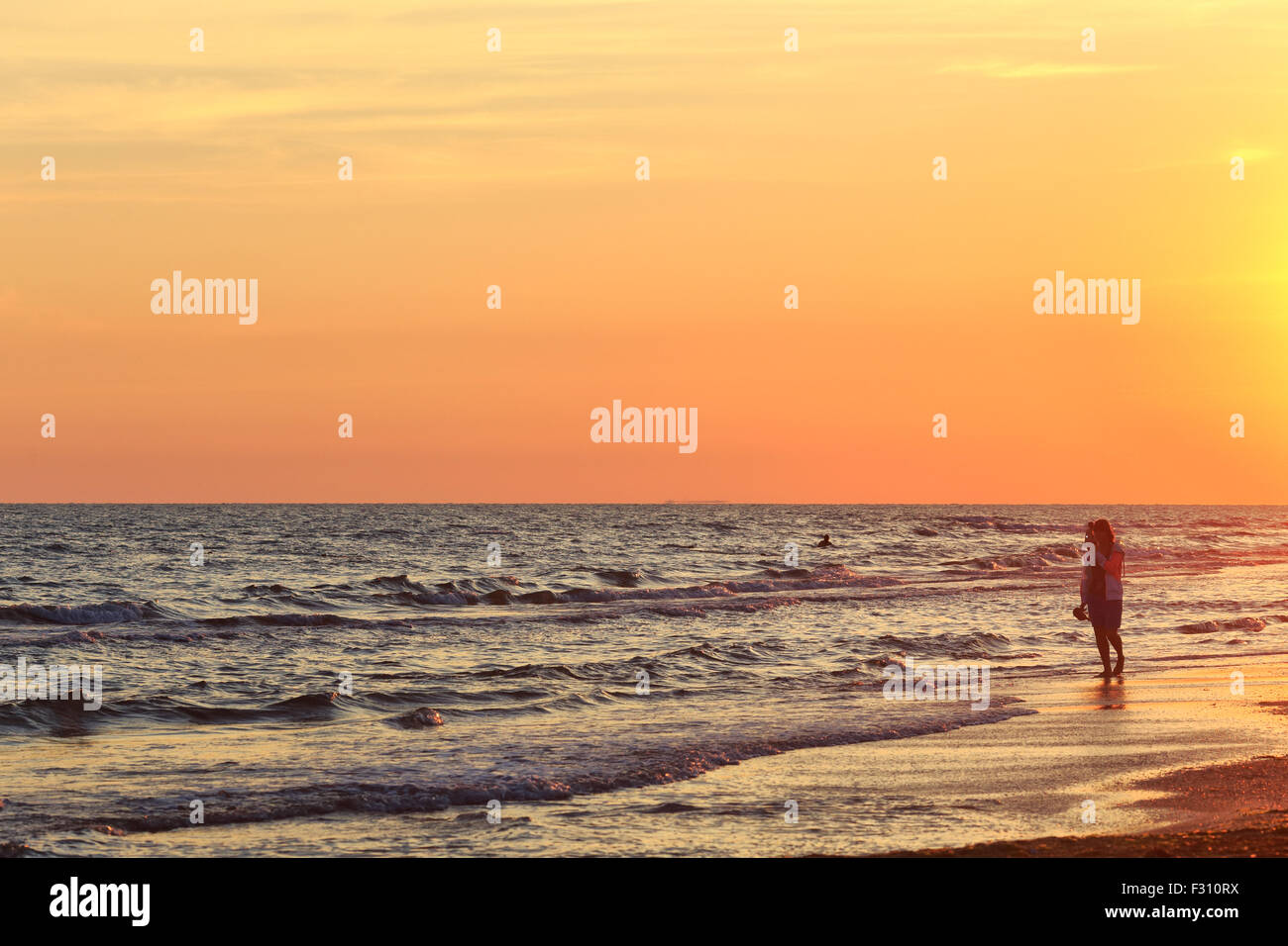 People walking on the beach at sunset Stock Photo - Alamy