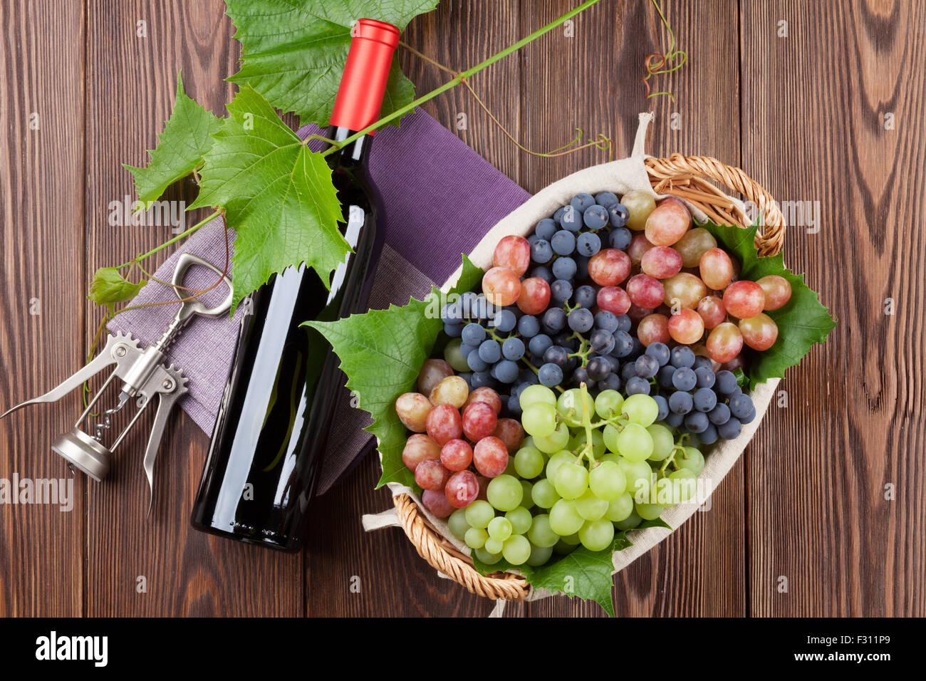 Red wine bottle and colorful grapes on wooden table. Top view Stock ...