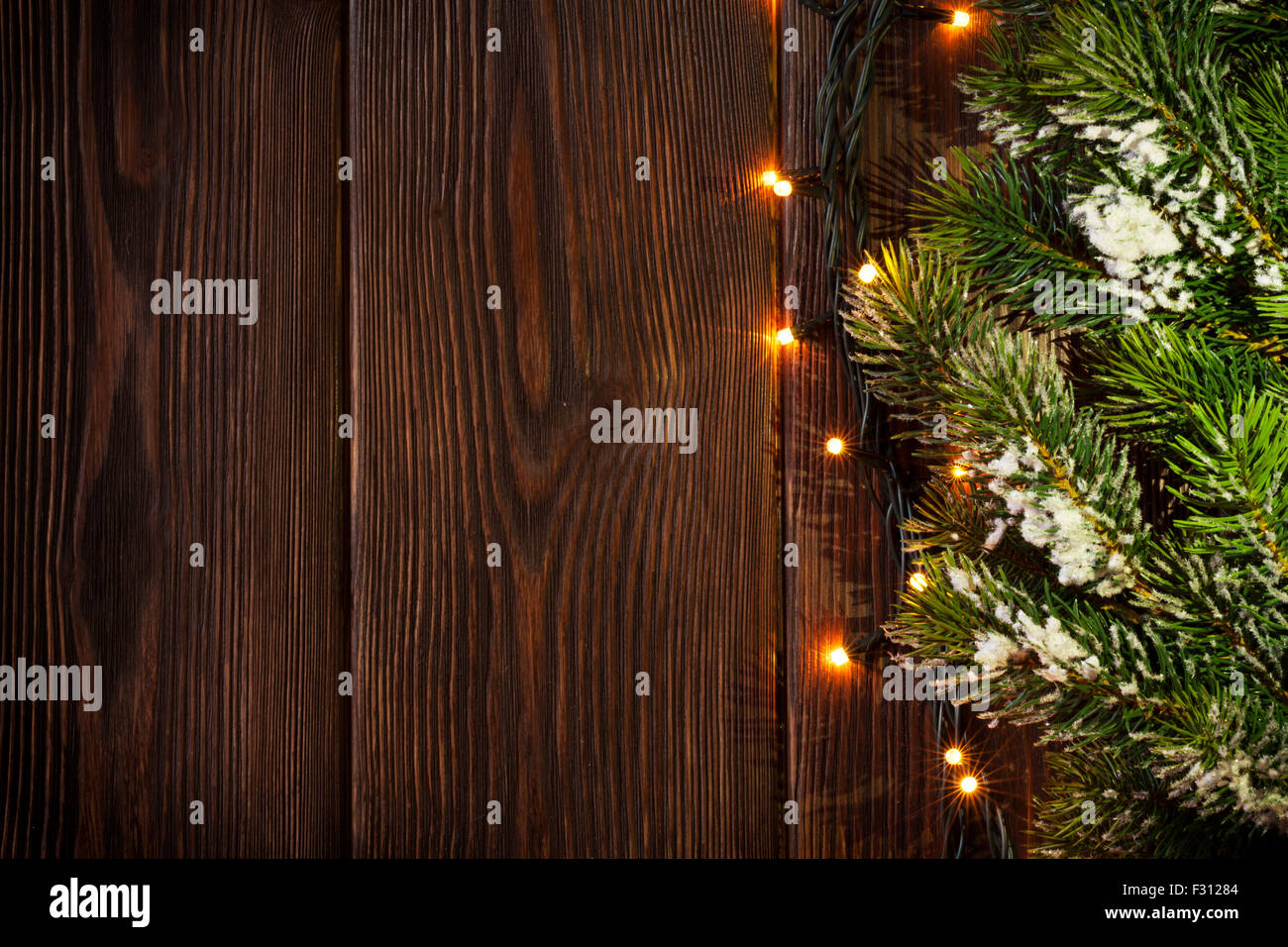 Christmas tree branch and lights on wooden background. View with copy ...
