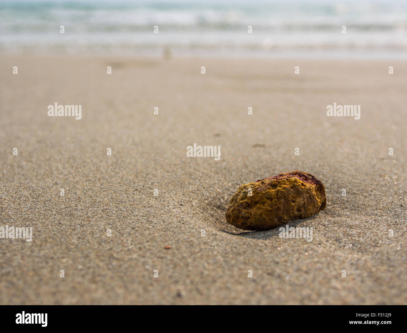 Red rock on the beach with blur sea background Stock Photo - Alamy