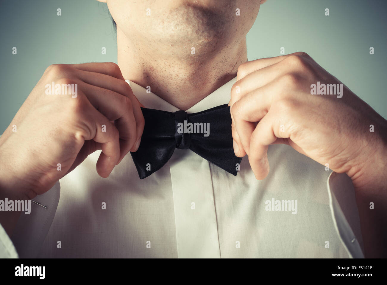 Closeup on a young man as he is tying a bow tie Stock Photo - Alamy