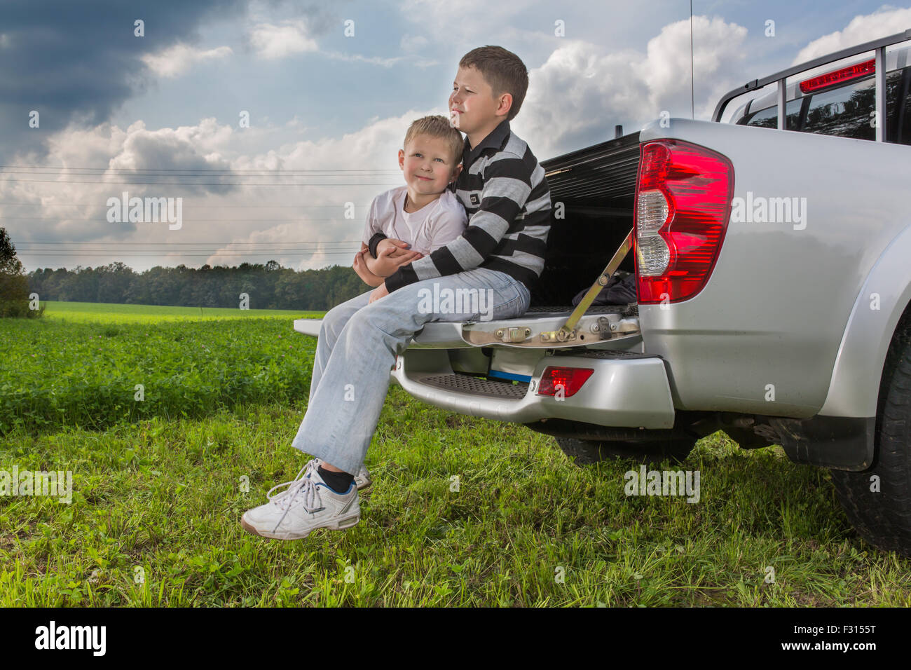 Two brothers siiting on a car trunk natural background Stock Photo - Alamy