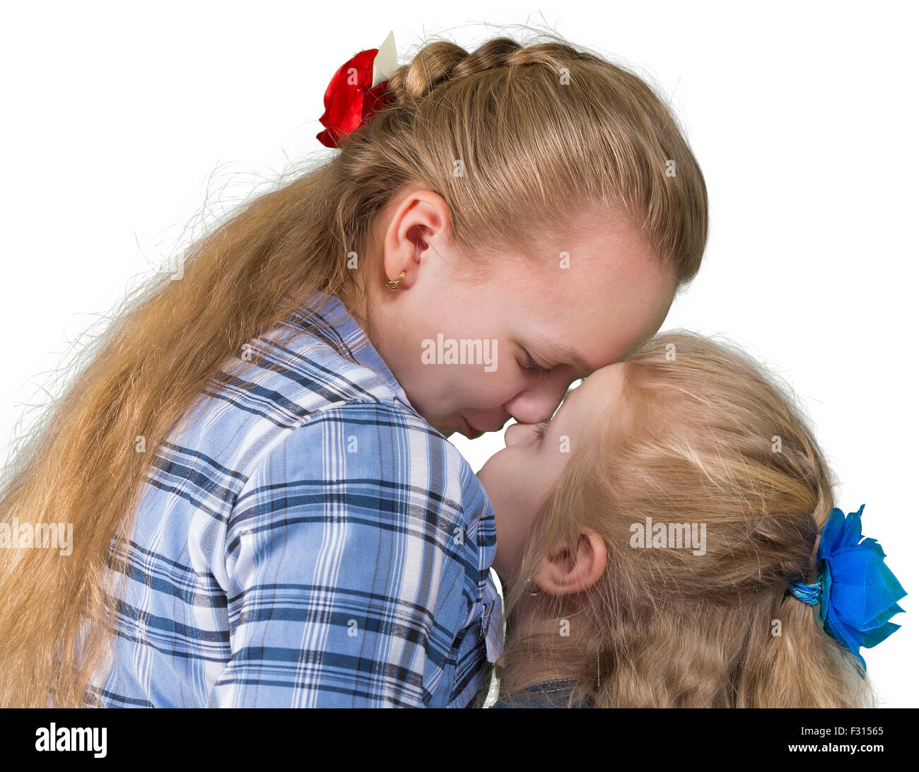 Senior and junior sisters embracing and kissing on white background ...