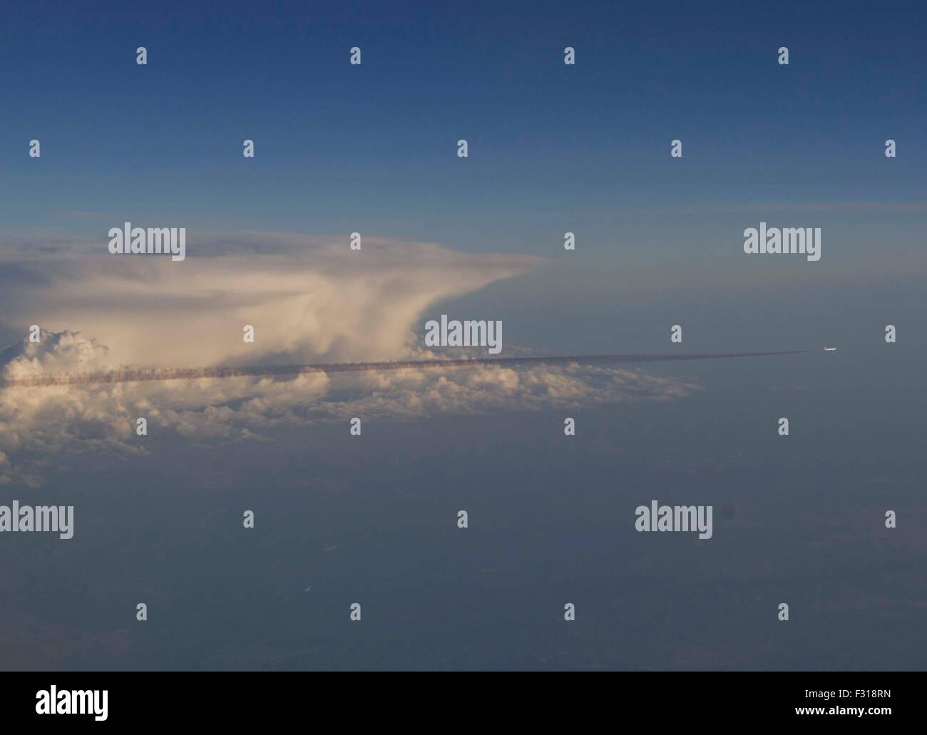 An airplane flying in the sky through the clouds and its contrail. View ...