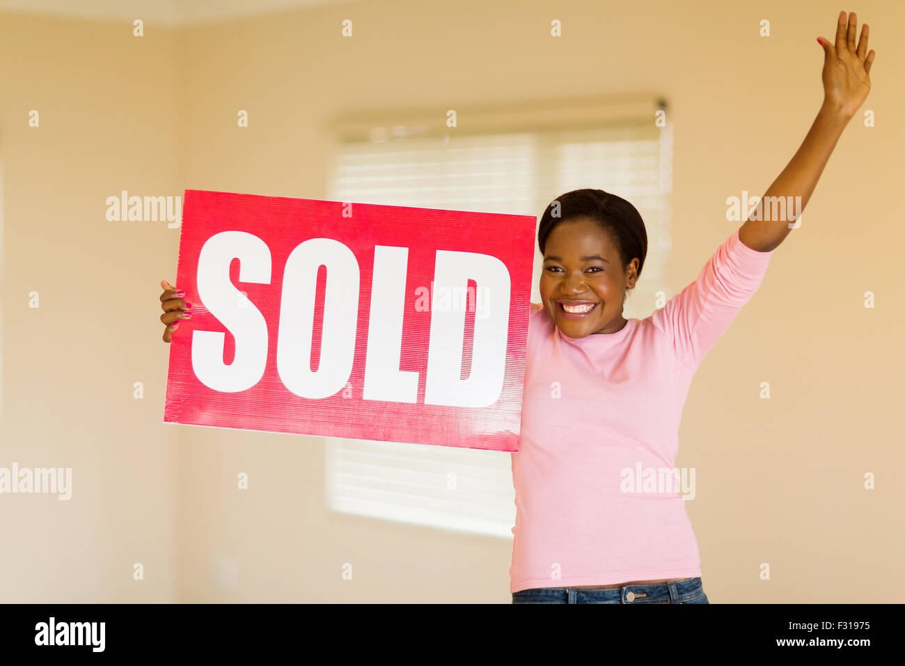 excited young African American woman with sold sign indoors Stock Photo ...
