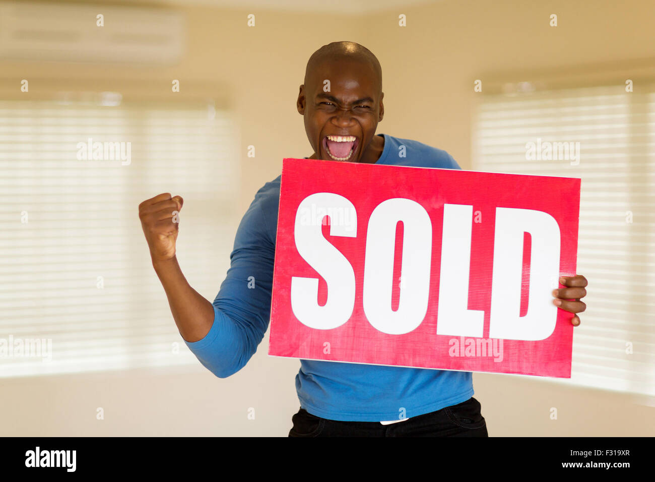 excited African man holding sold sign in his house Stock Photo - Alamy