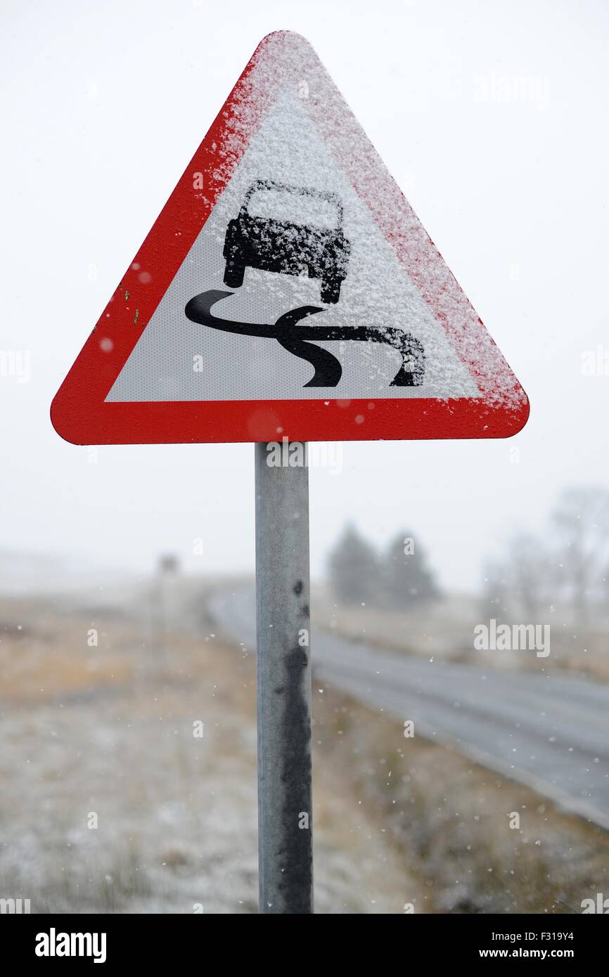A road sign covered in snow warning car drivers of hazardous driving ...