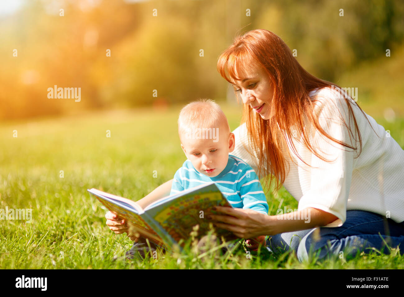 Mother with son reading book in park Stock Photo - Alamy