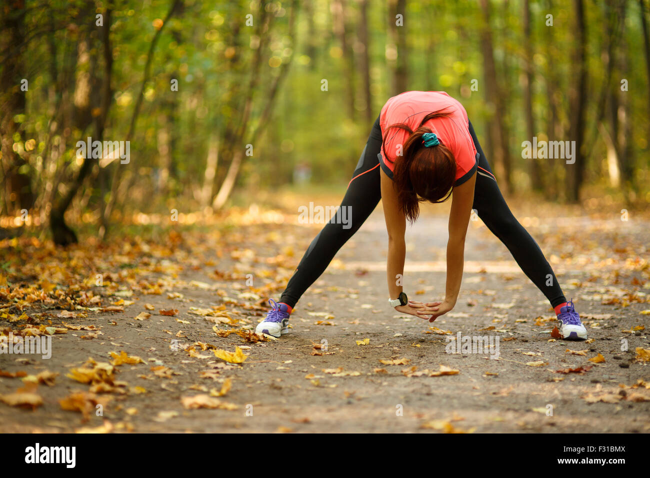 Beautiful young woman doing stretching exercise on road at park Stock Photo - Alamy