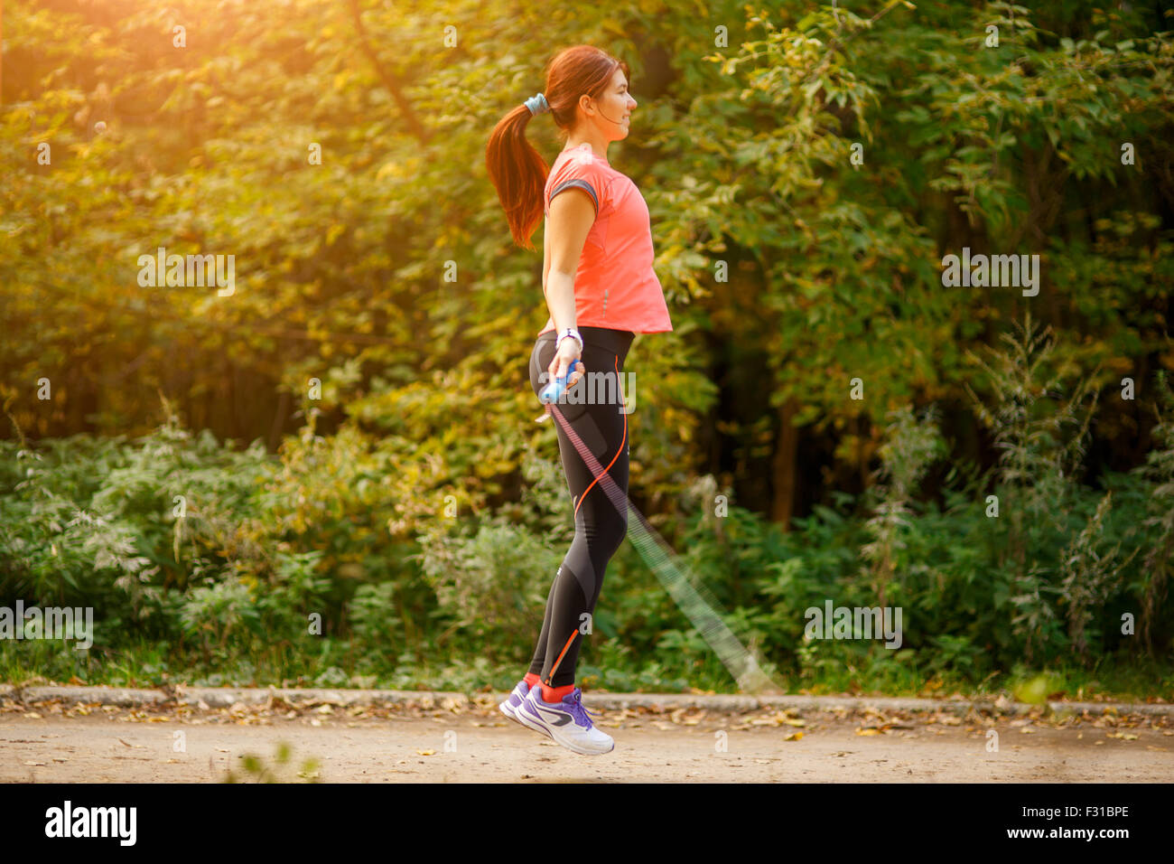athletic young woman skipping with jump rope in park on summer day ...