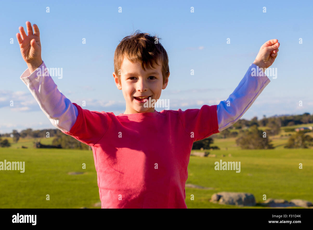 Happy boy with arms up standing in a green field Stock Photo - Alamy