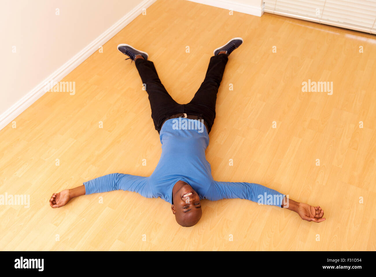 overhead view of young African man lying on the floor in his new home ...